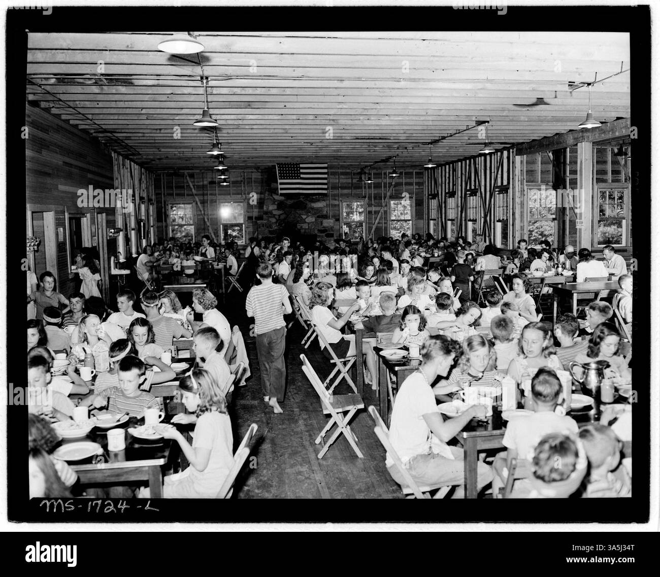 This 1946 image shows campers eating a noon-day meal in the dining hall ...