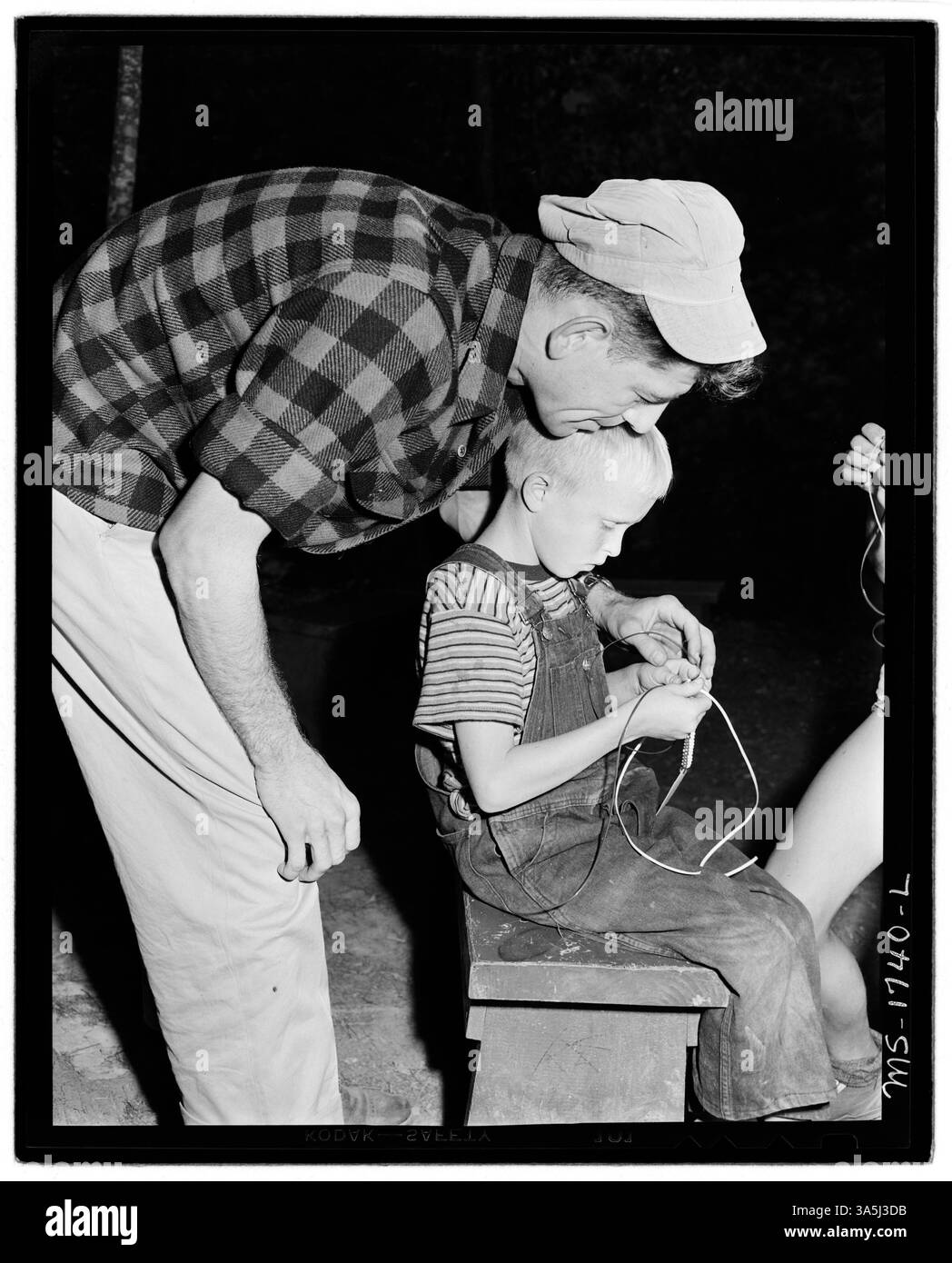 Carl Mack, senior counselor, instructs a young camper in beadwork at ...