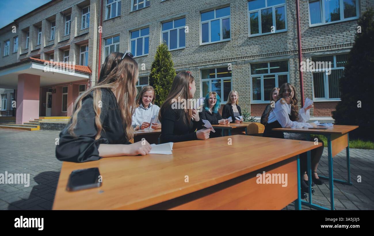 High school students are taking an exam at desks outside in the fresh ...