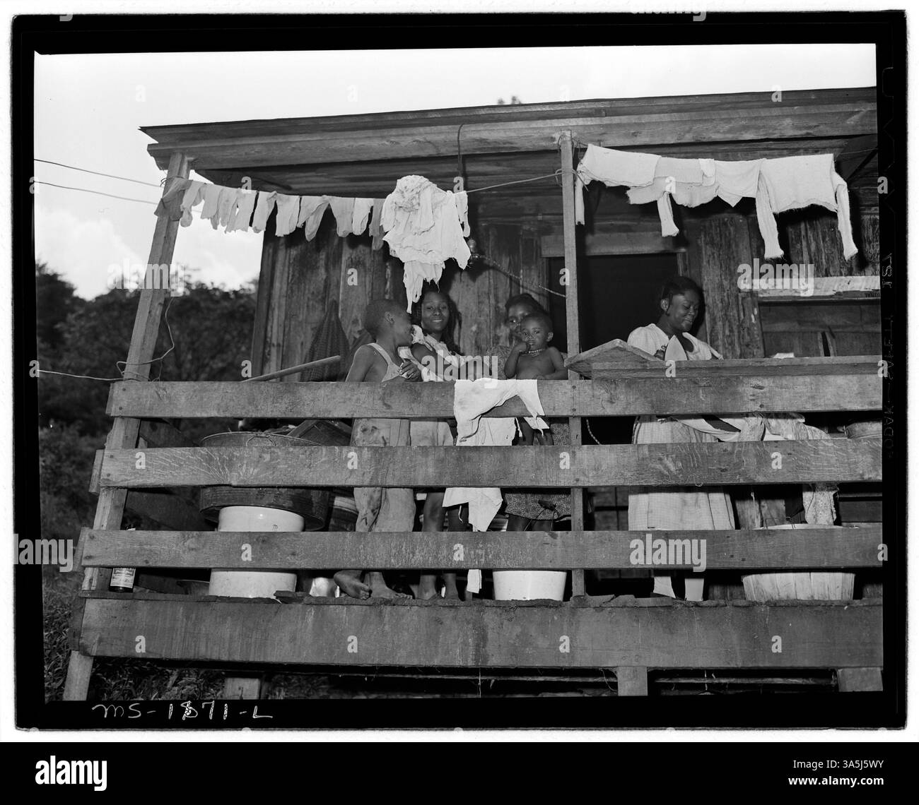 Mrs. Lawson Mayo and her children on the porch of their four-room house ...