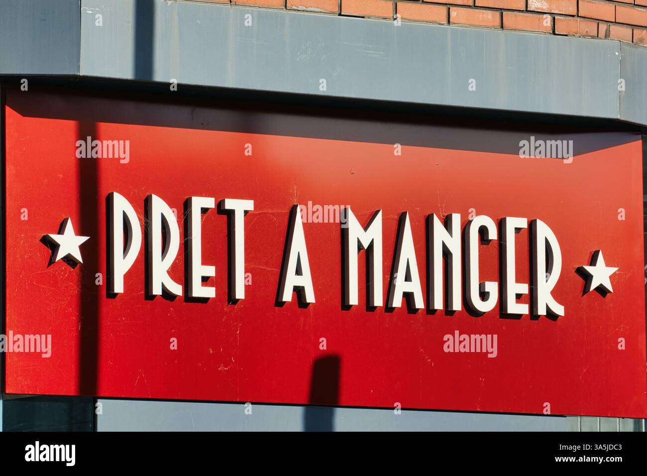 A close-up shows a "Pret A Manger" sign with red background, white text ...