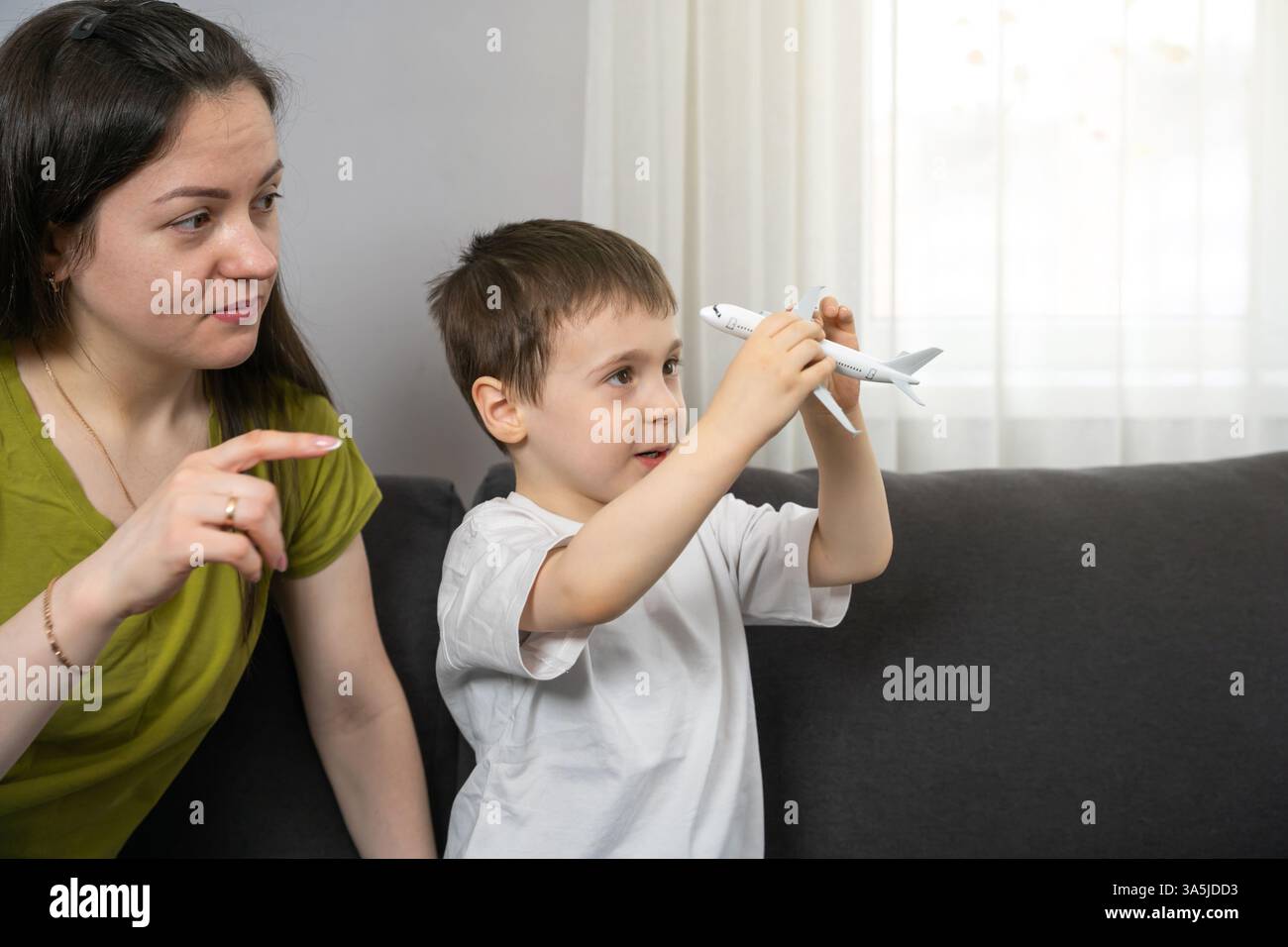 A boy studies a figurine of a passenger plane with his mother ...