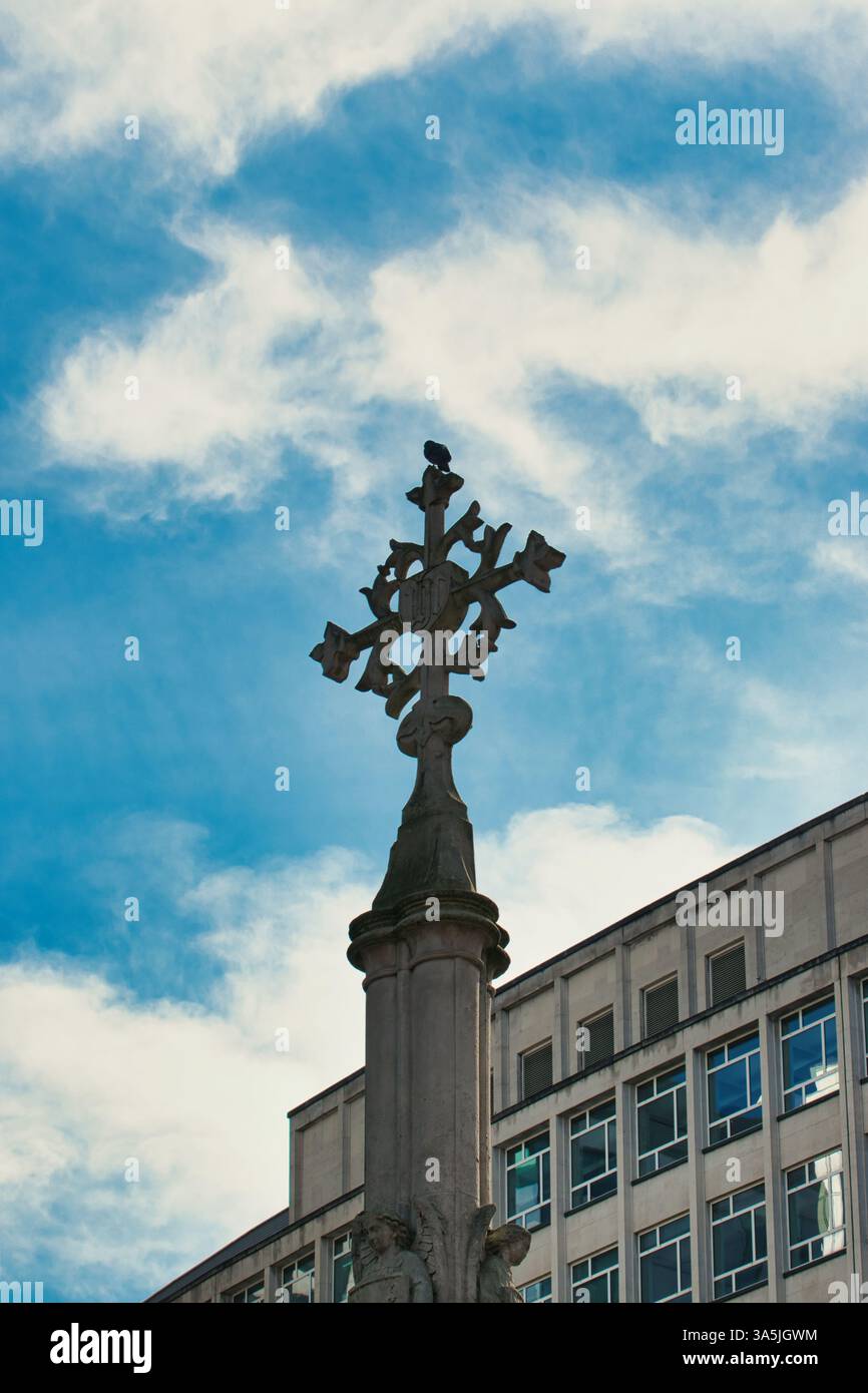 Stone monument with ornate cross topped by a bird, set against a blue ...