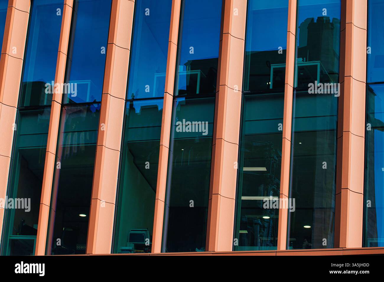 Close-up of a modern building facade with blue glass windows and salmon ...
