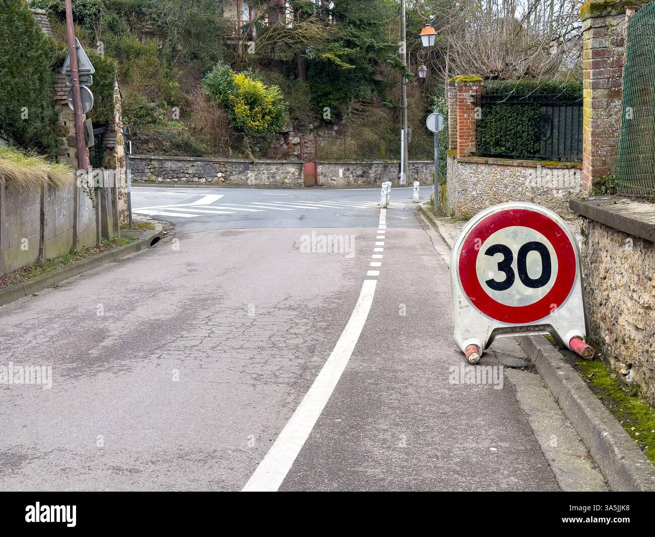 Roadside view showing a speed limit sign in a quiet village setting on ...