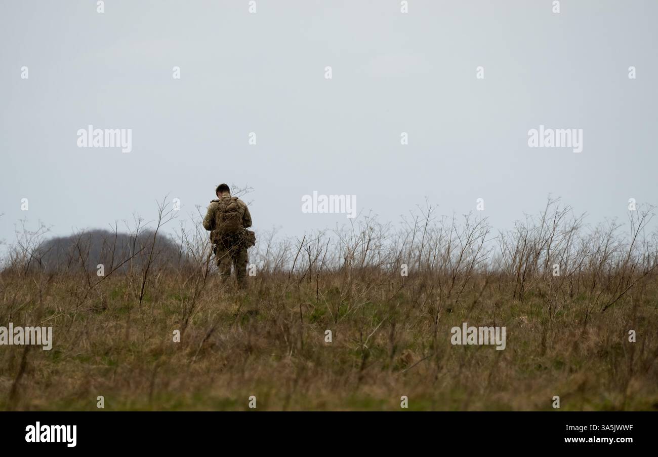 British army soldier moving across tall grass meadow Stock Photo - Alamy