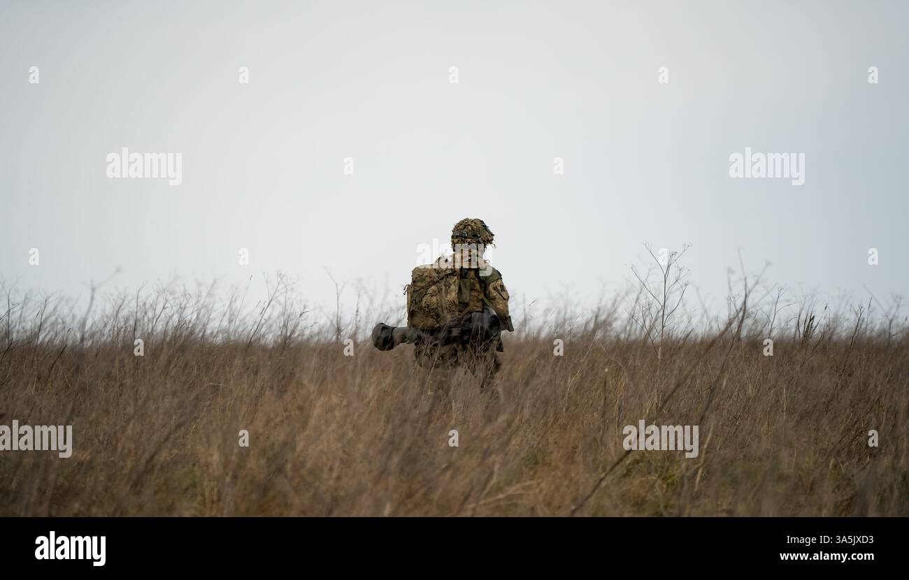 British army soldier with N-LAW combat equipment moving across tall ...