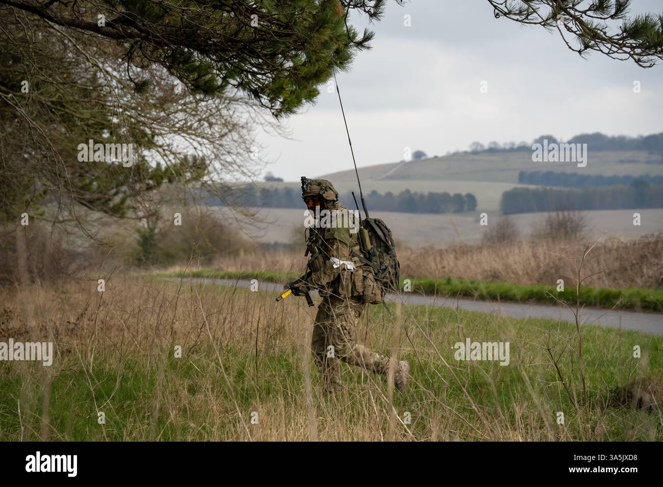 British army soldier with full combat equipment moving across tall ...