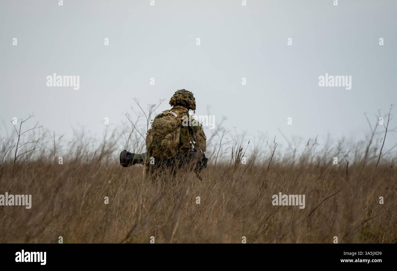 British army soldier with N-LAW combat equipment moving across tall ...