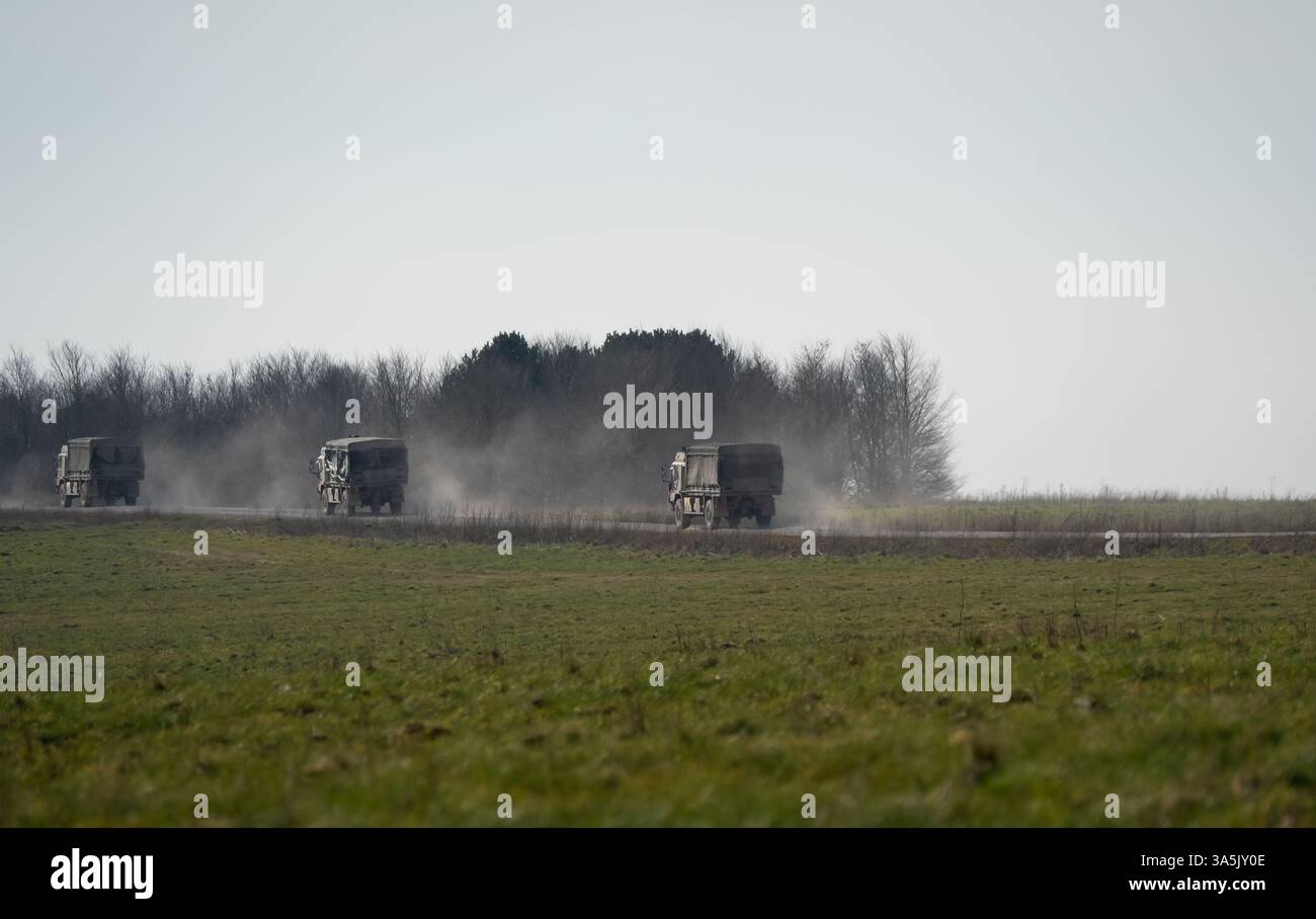 a convoy of British army MAN SV 4x4 dark green trucks moving along a ...