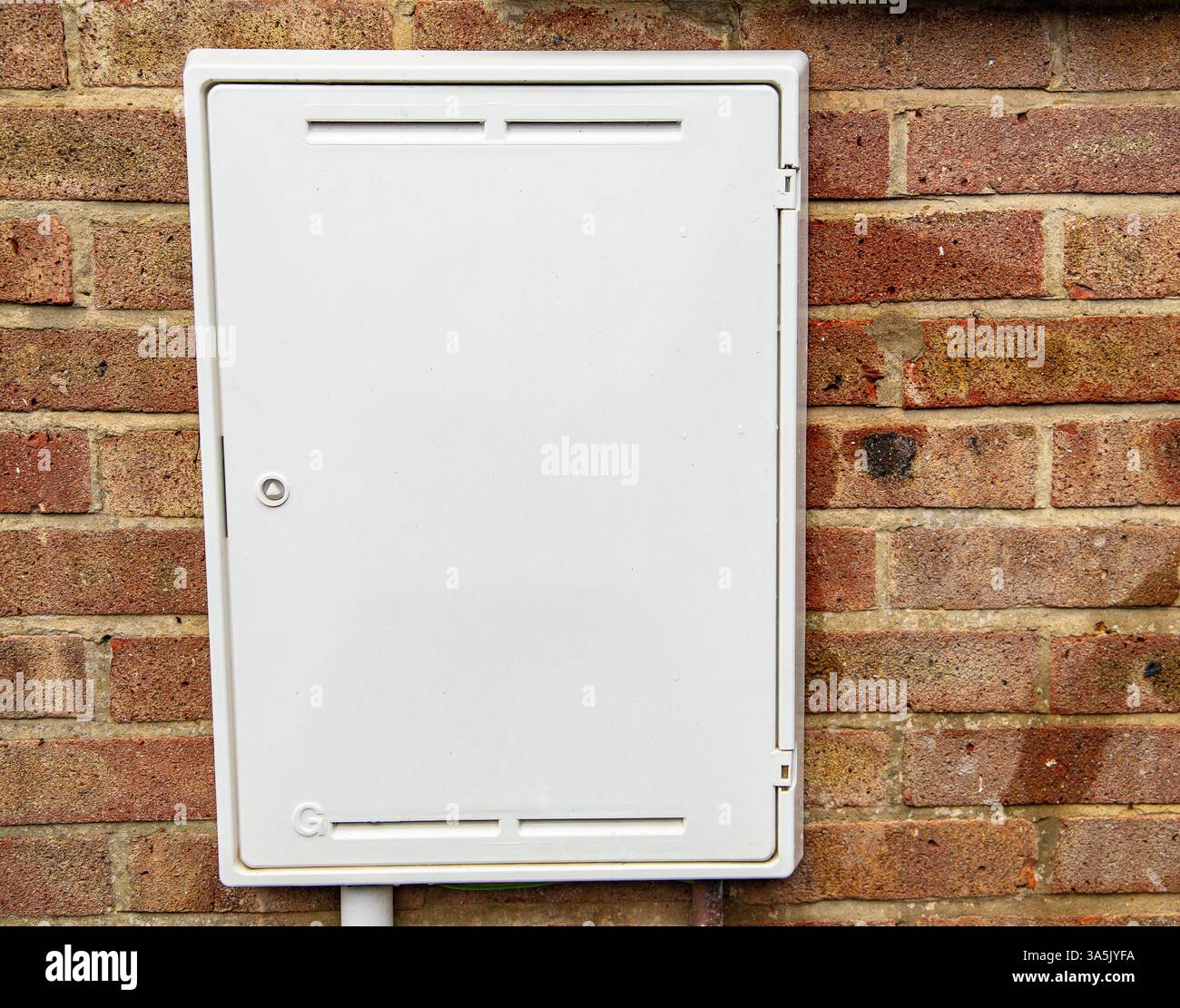 White utility box mounted on a red brick wall, featuring a secure metal ...