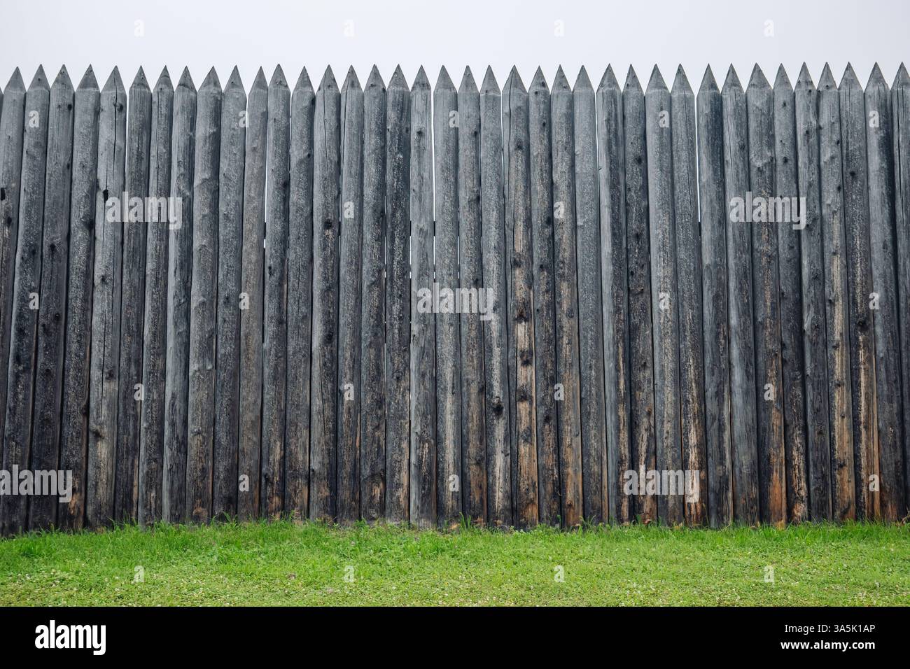 Weathered wooden palisade protecting verdant grassland, marking ...