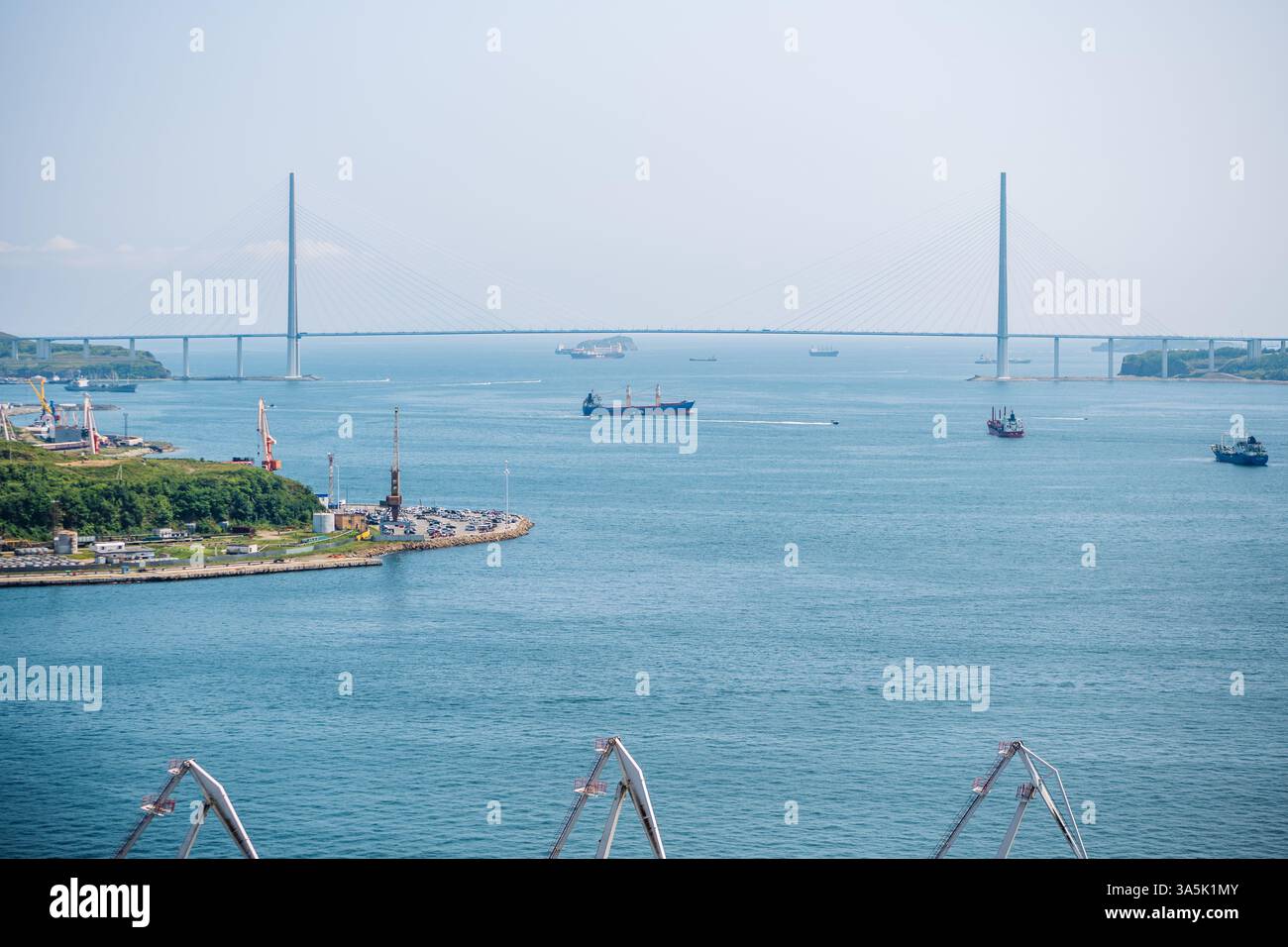 Cargo ships sailing gracefully beneath the russian bridge on a bright ...