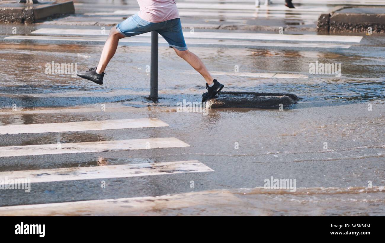 Tourist jumping across waterlogged intersection, preventing wet shoes ...