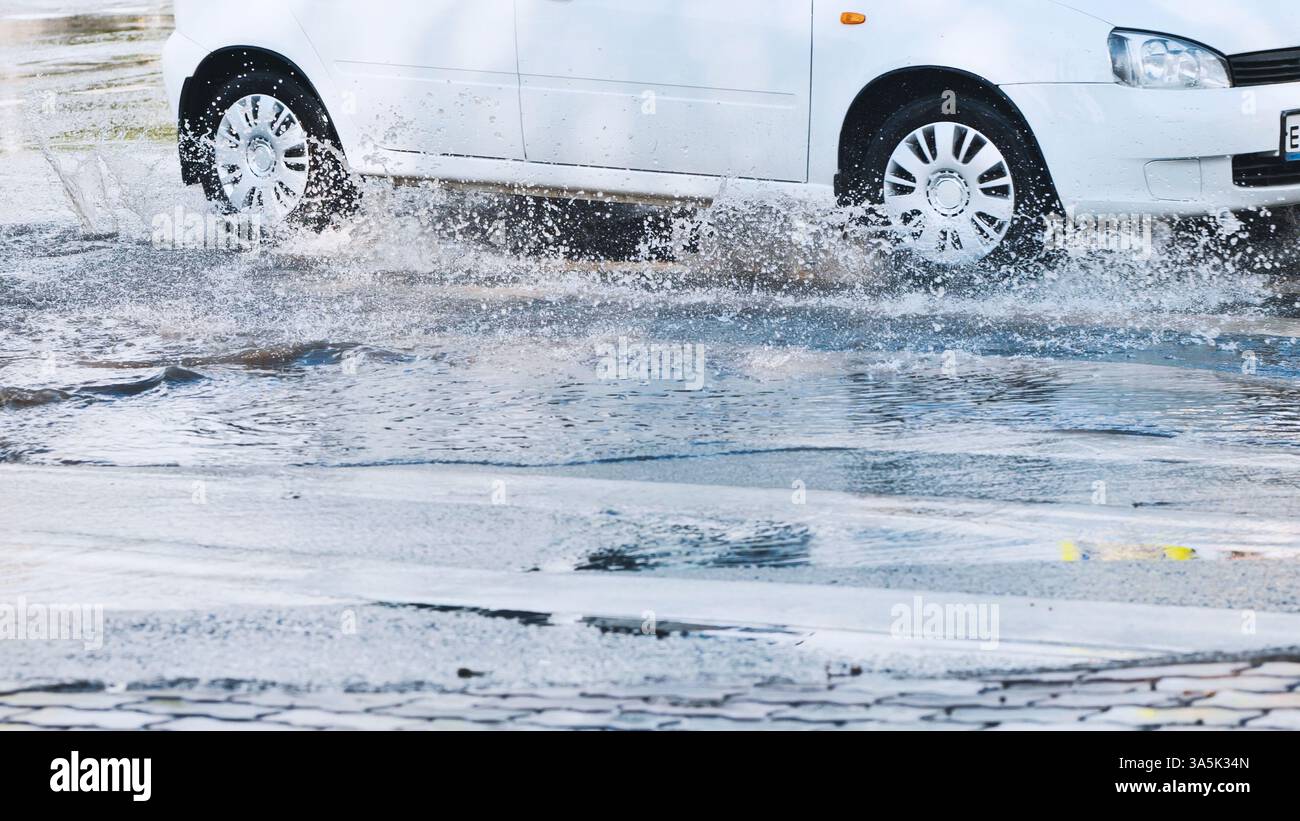Fast white vehicle splashing water while driving through roadside ...