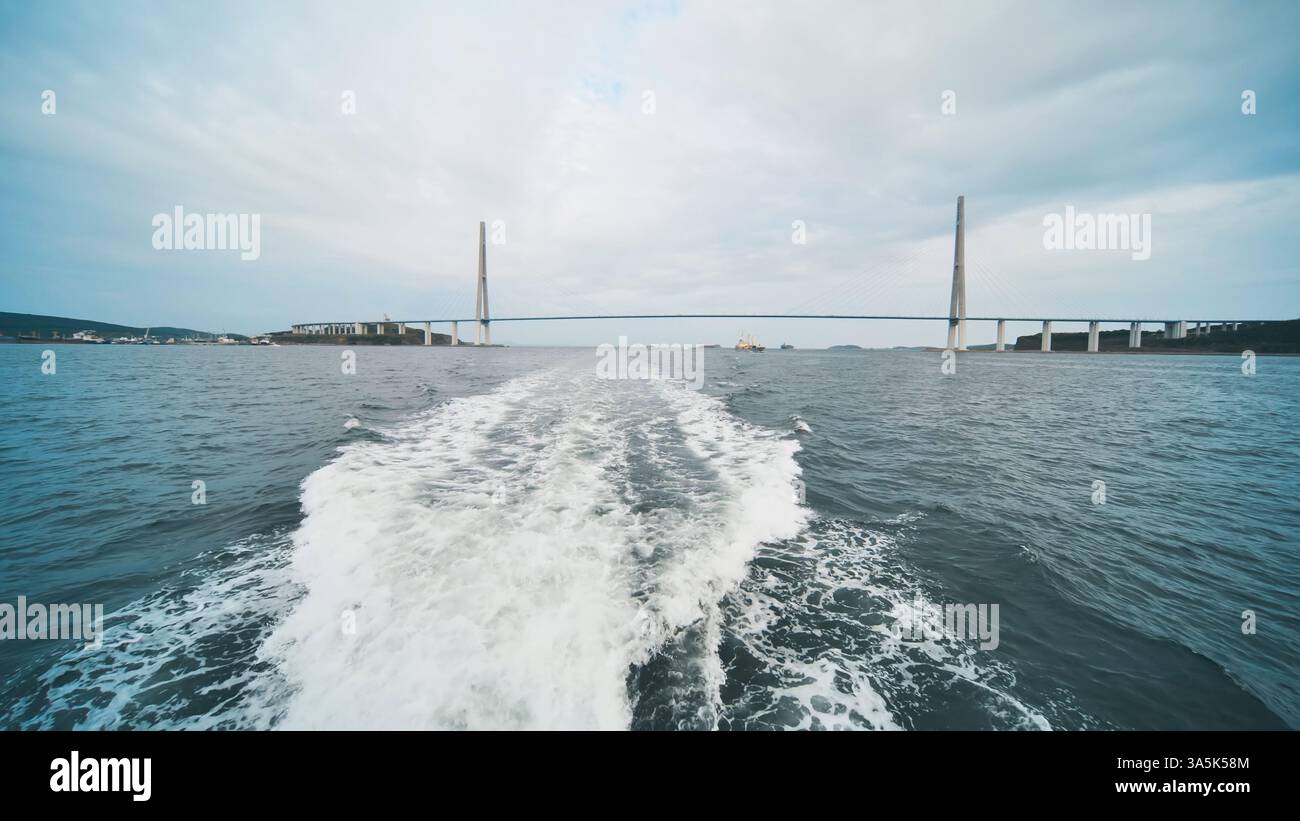 Russky bridge viewed from motorboat, creating white foamy wake against ...