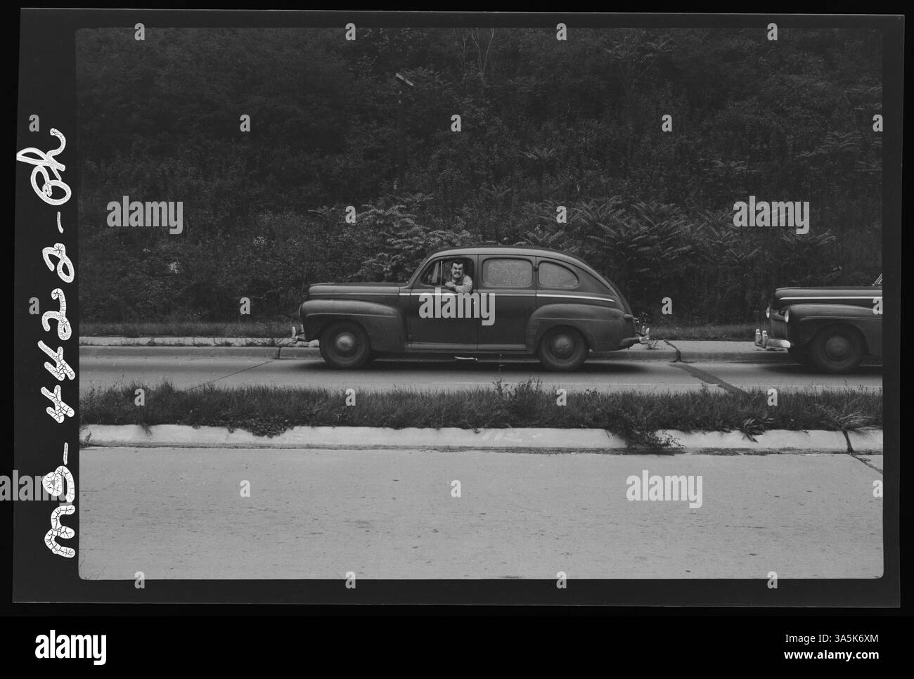 This photograph captures a man leaning out of the driver's side window ...