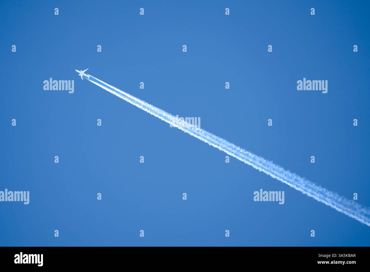 a twin engined jet liner aircraft in deep blue sky, contrails vapour ...