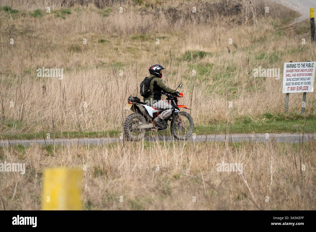 a motor cyclist (biker) riding their sports trail motorbike along a ...
