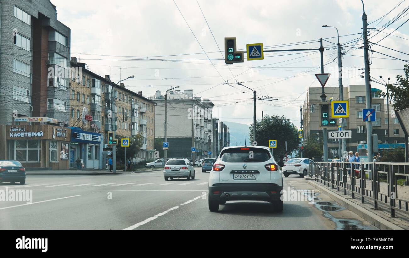 Crossover vehicle navigating urban street, passing pedestrian crossing ...
