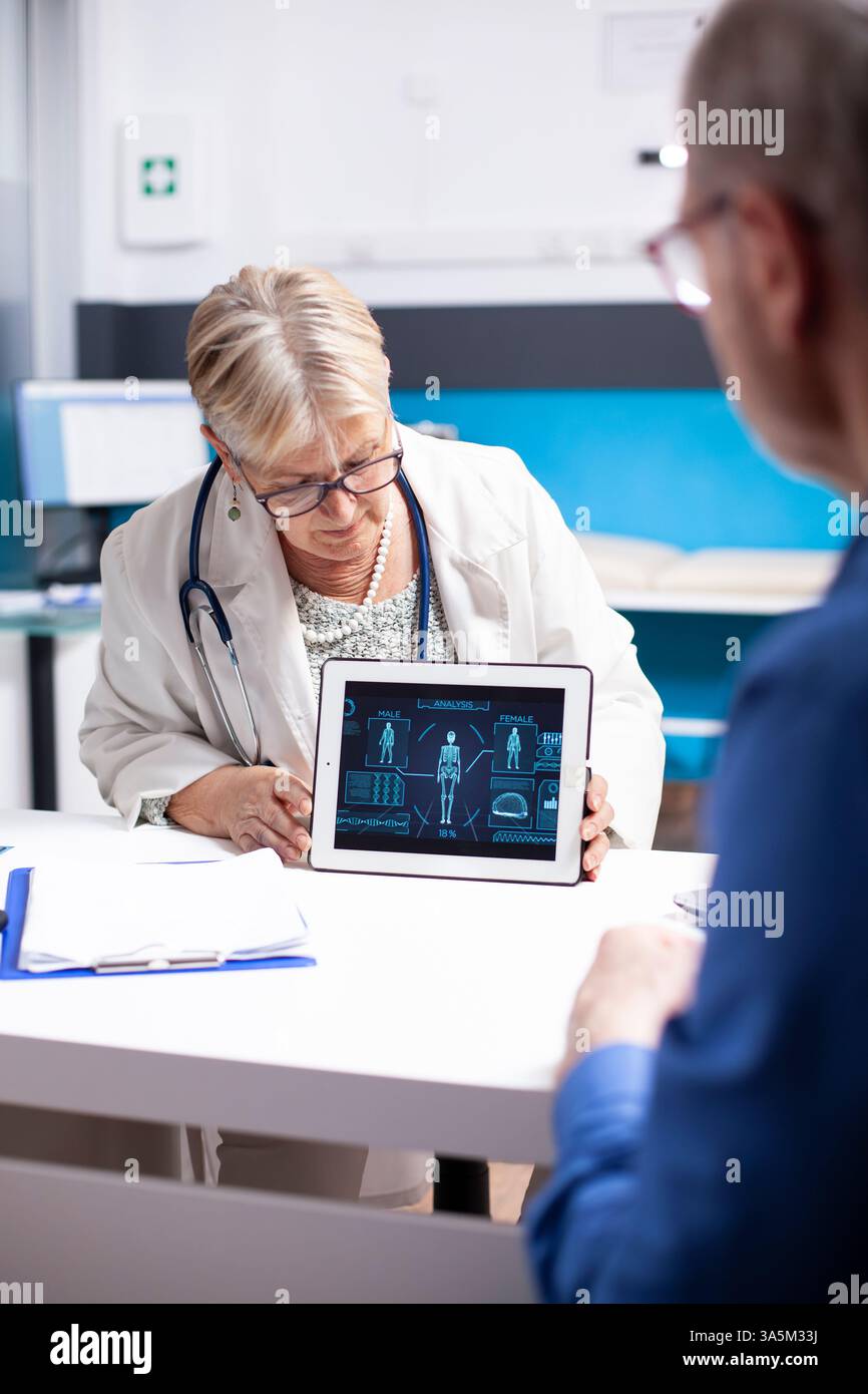 Old female physician uses digital device to illustrate healthcare ...