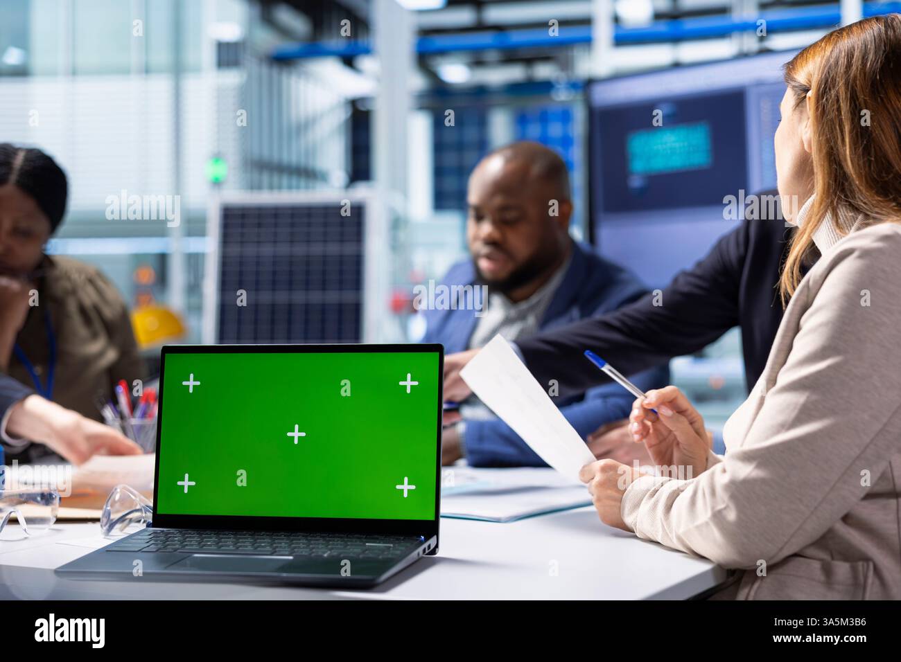 Production plant colleagues look over research and development data on mockup notebook ...