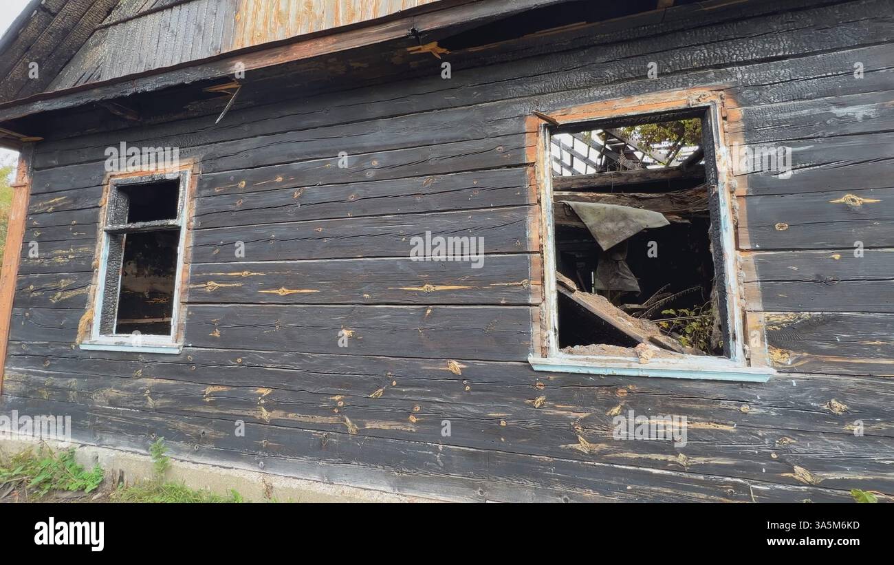 Burnt wooden house with broken windows showing charred remains of roof ...