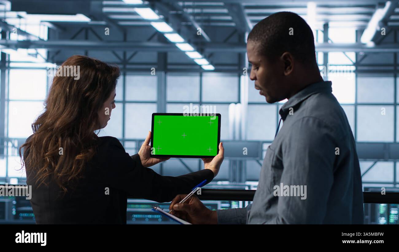 System administrators in server farm using isolated screen mockup tablet to verify settings ...