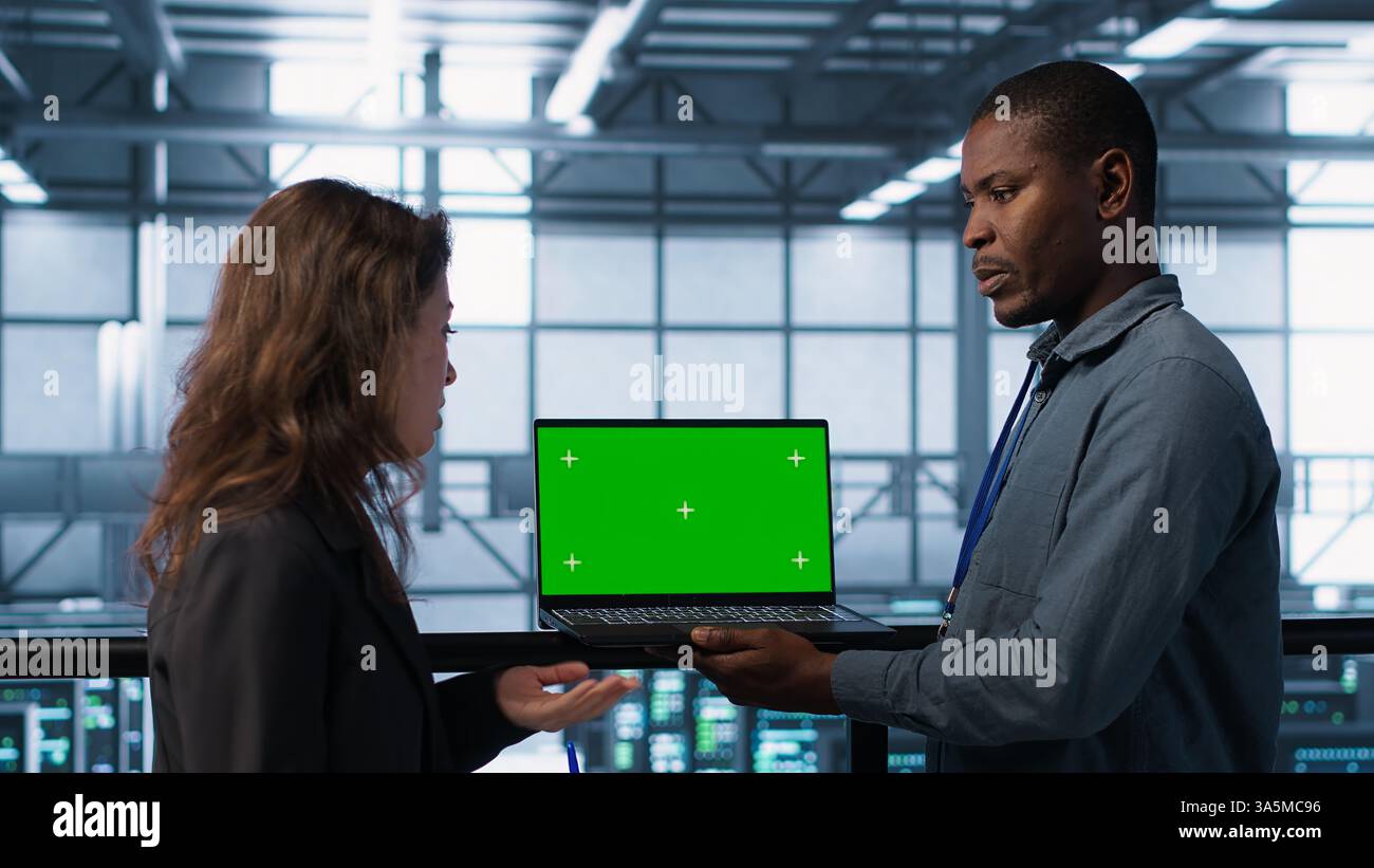 Technicians in data center using green screen mockup laptop to develop ...