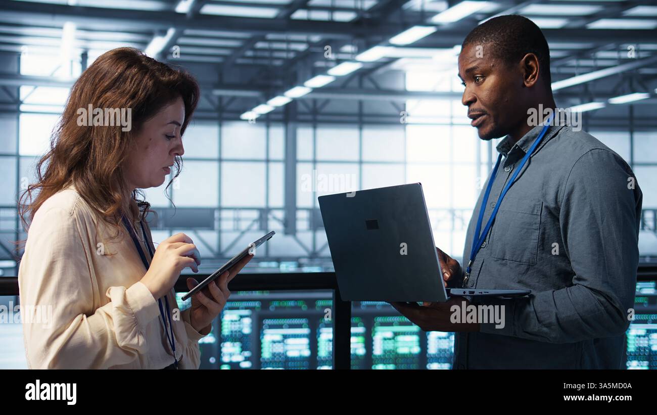 Team Of Technicians Working In Server Farm Using Laptops To Analyze Data Teamworking Workers