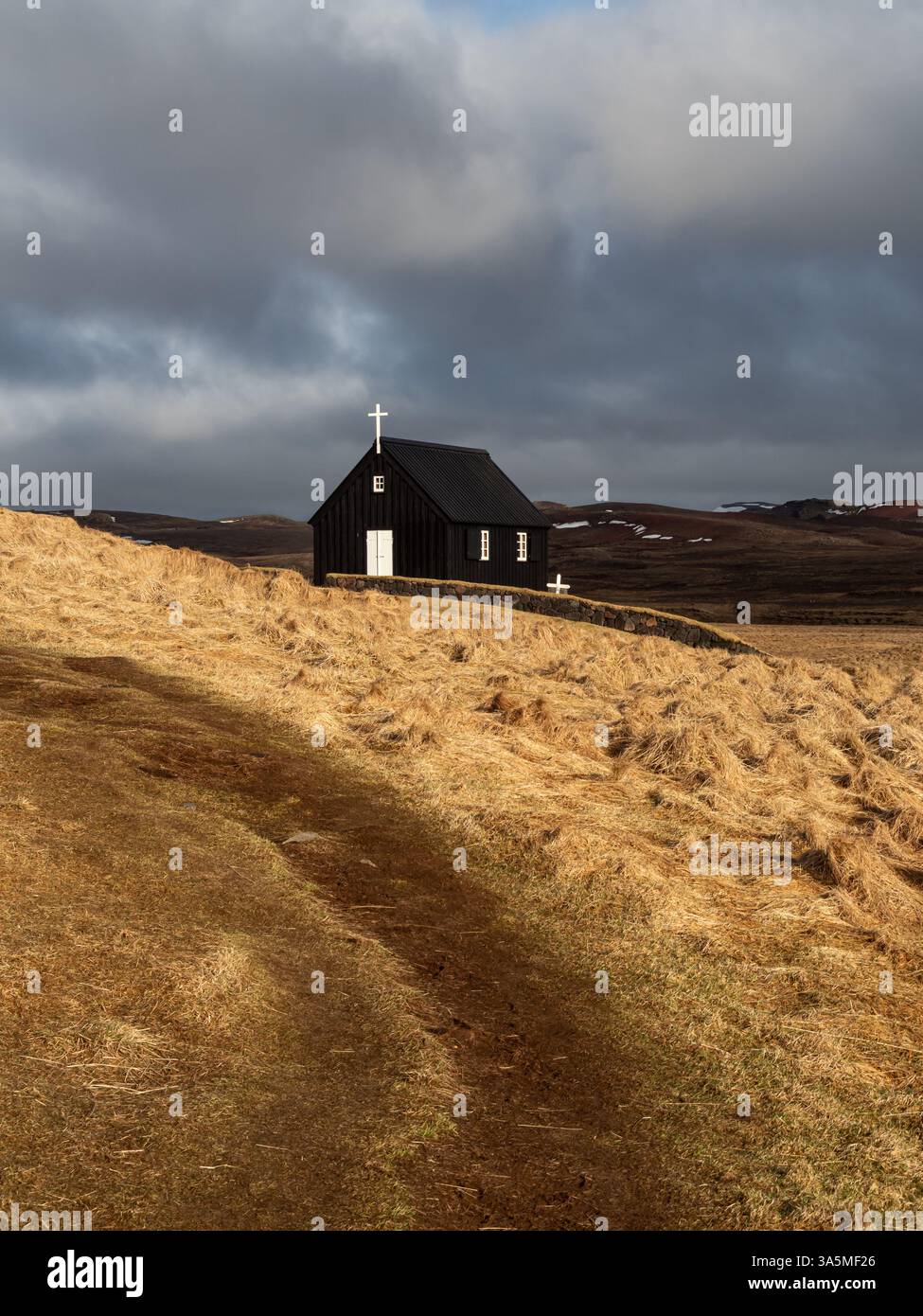 A winding path leads to Krýsuvíkurkirkja, a black church nestled in ...