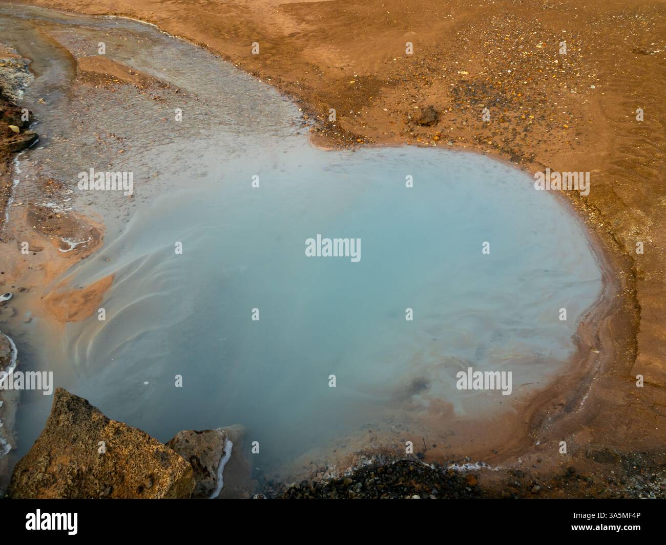 A milky-blue geothermal pool in Seltún, Iceland, framed by vibrant ...