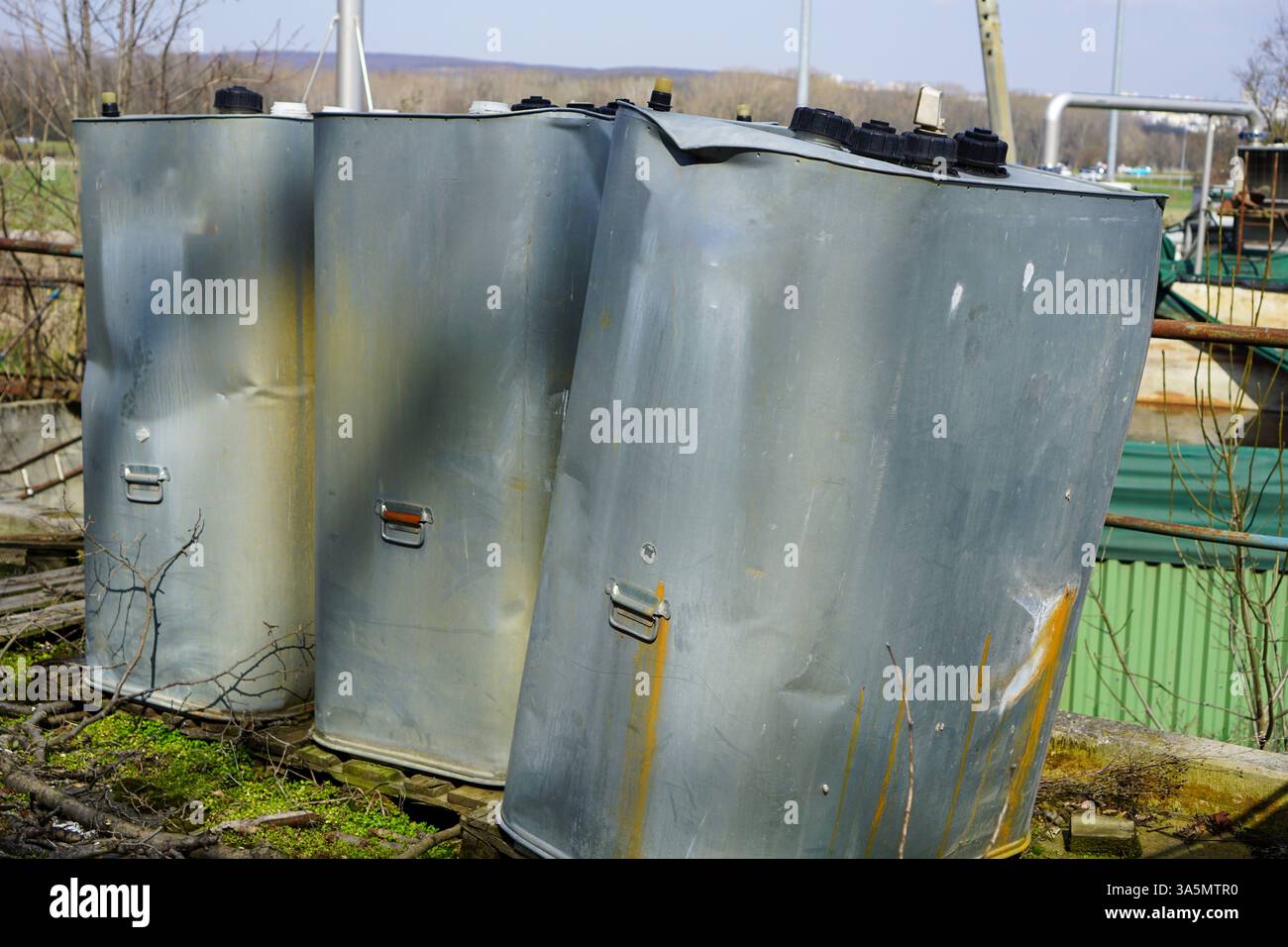 Three large, damaged metal tanks with visible dents, rust, and ...