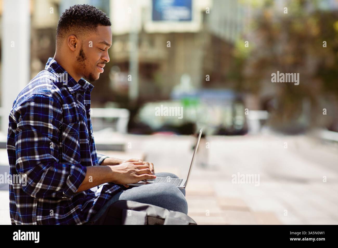 Black man using laptop, sitting in downtown with gadget Stock Photo - Alamy