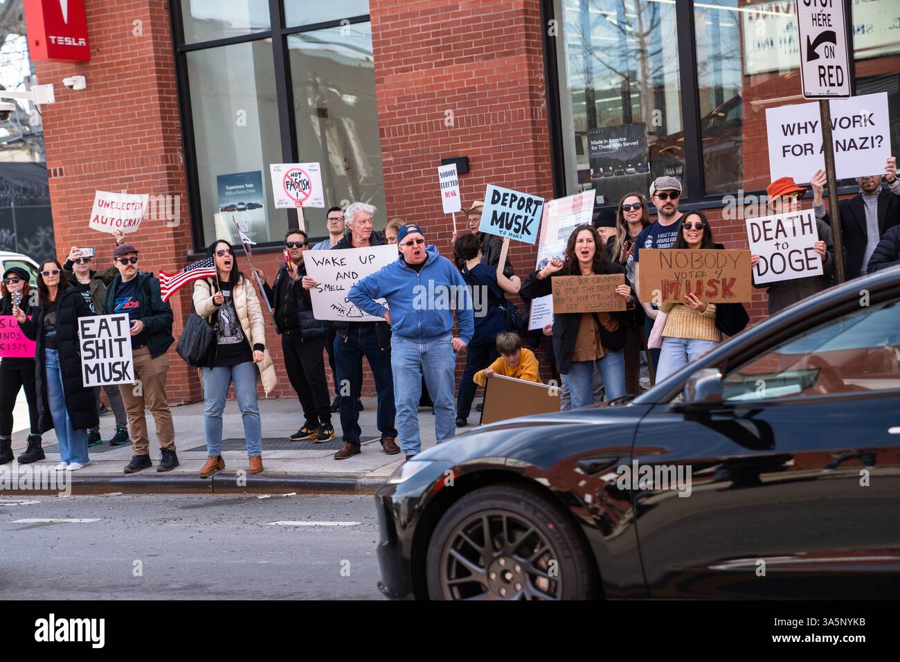 Mar 22, 2025; Brooklyn, NY, USA; Protestors heckle a passing Tesla ...