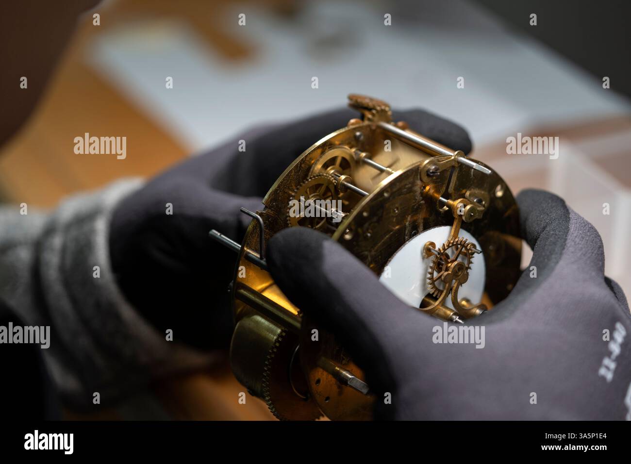 A restorer works on the mechanism of a antique clock in a workshop on ...