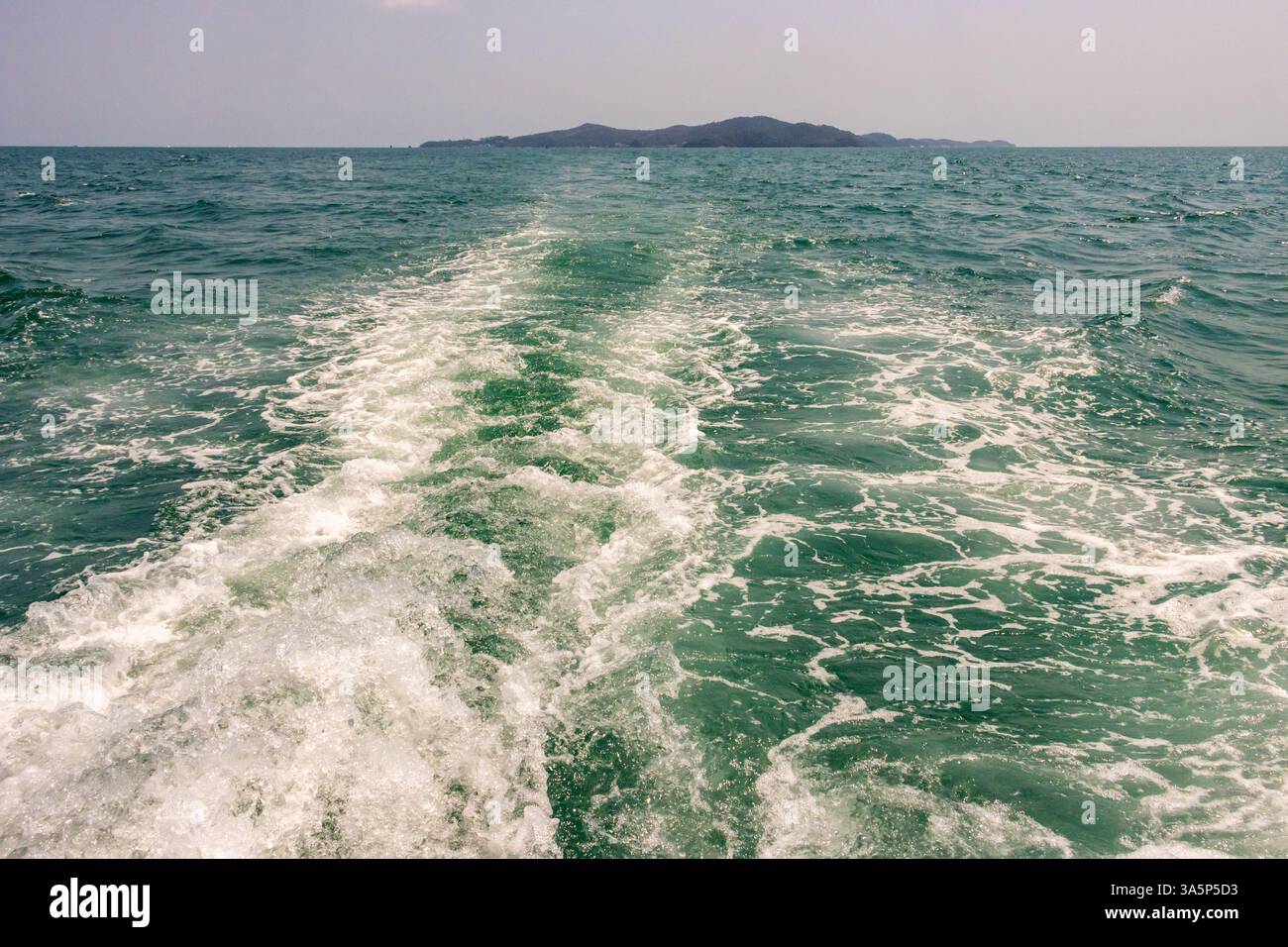 Water trail behind a tourist ship departing from a tropical island in ...