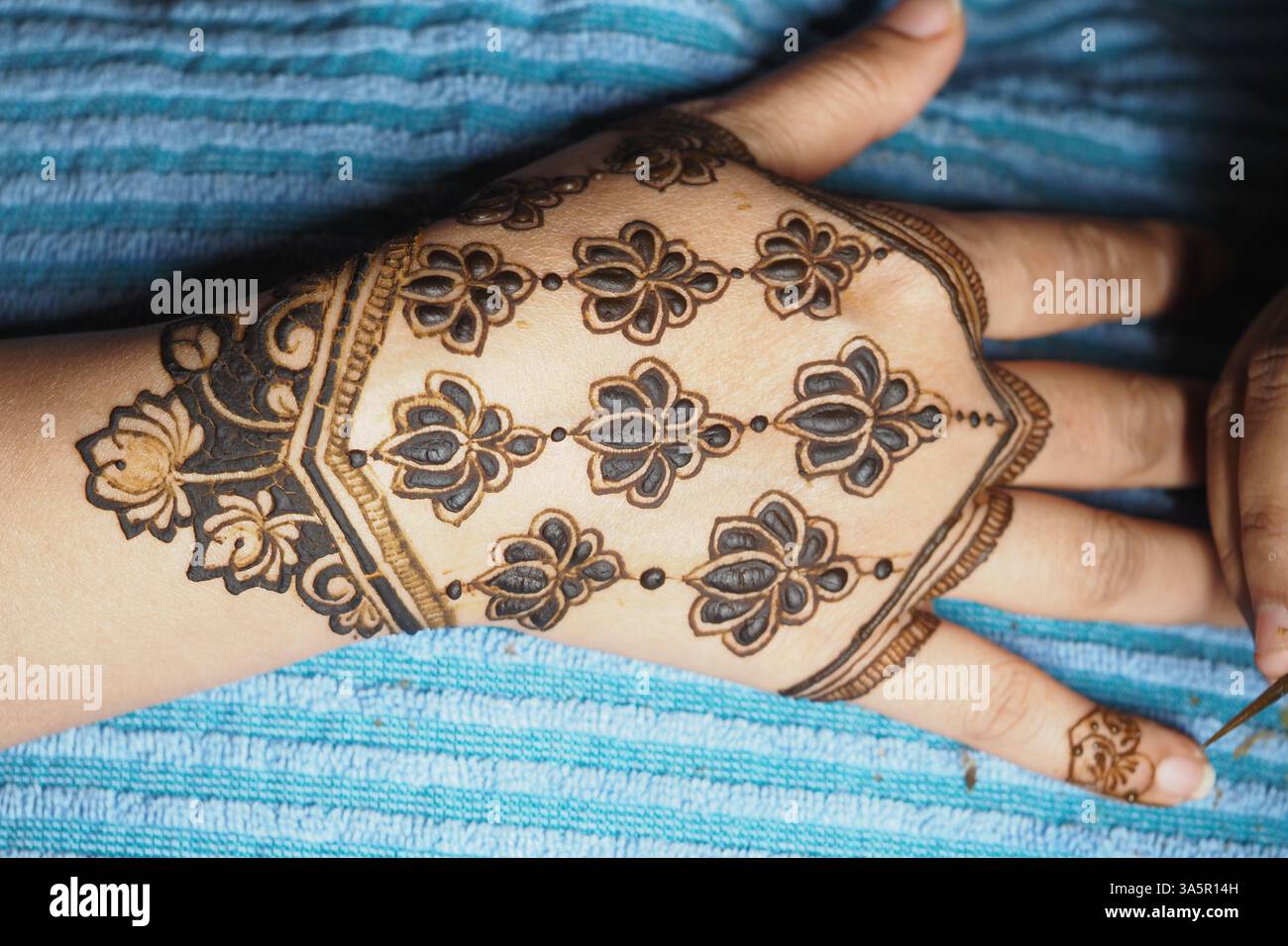 Floral henna design on hand with blue fabric backdrop Stock Photo - Alamy