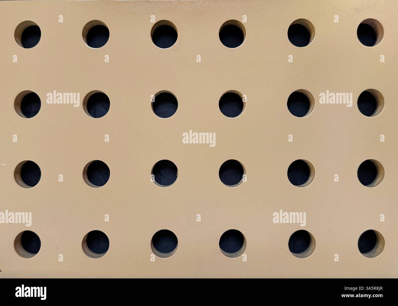 Close up of hole perforated panel in gold beige paint finish. Seamless ...