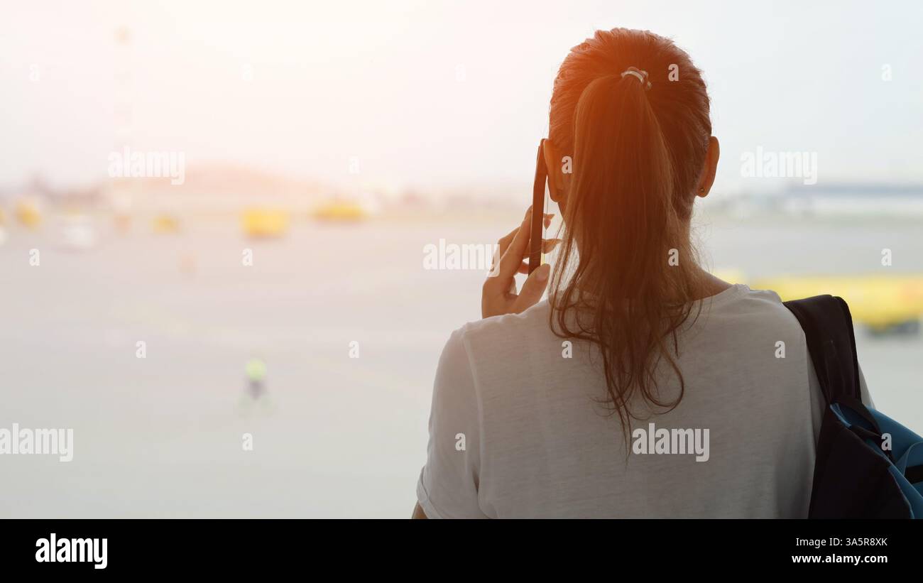 Lady calls on phone looking out window at aircraft movement area Stock ...