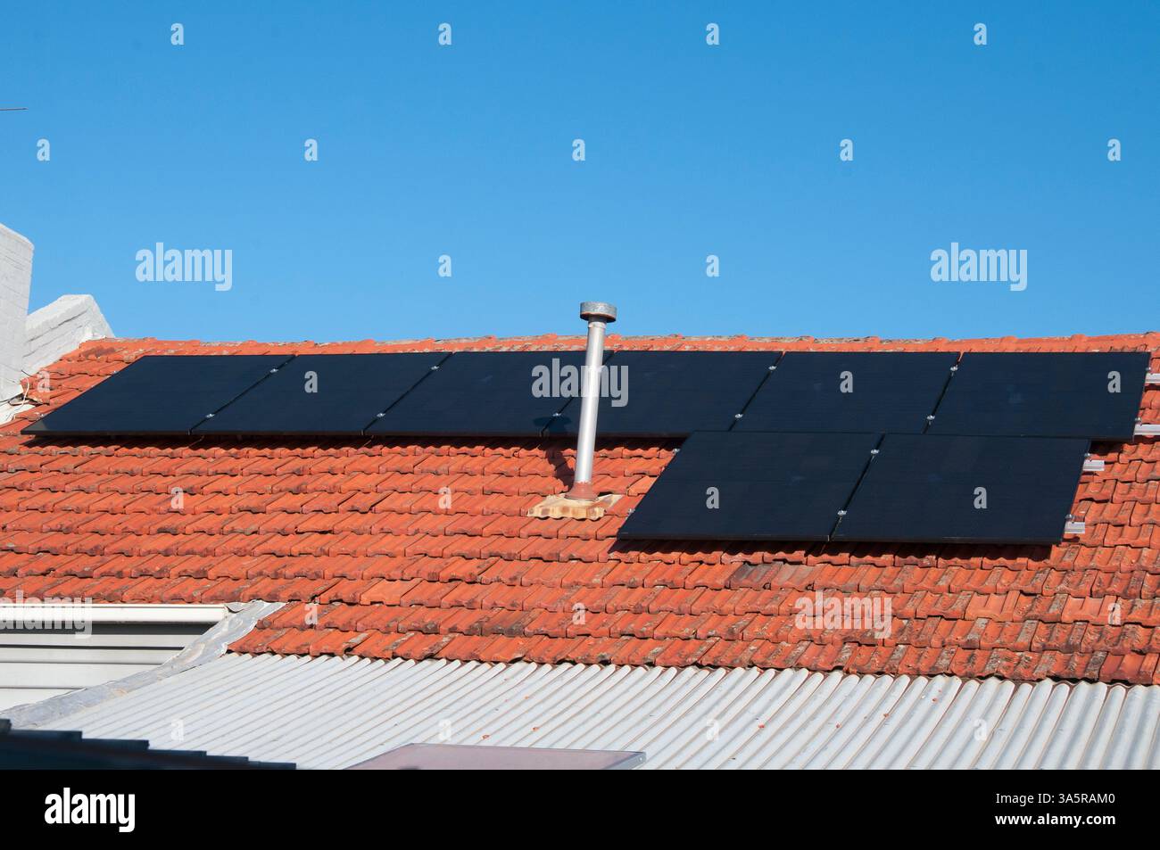 East-facing solar energy collector panels mounted on a tiled rooftop ...