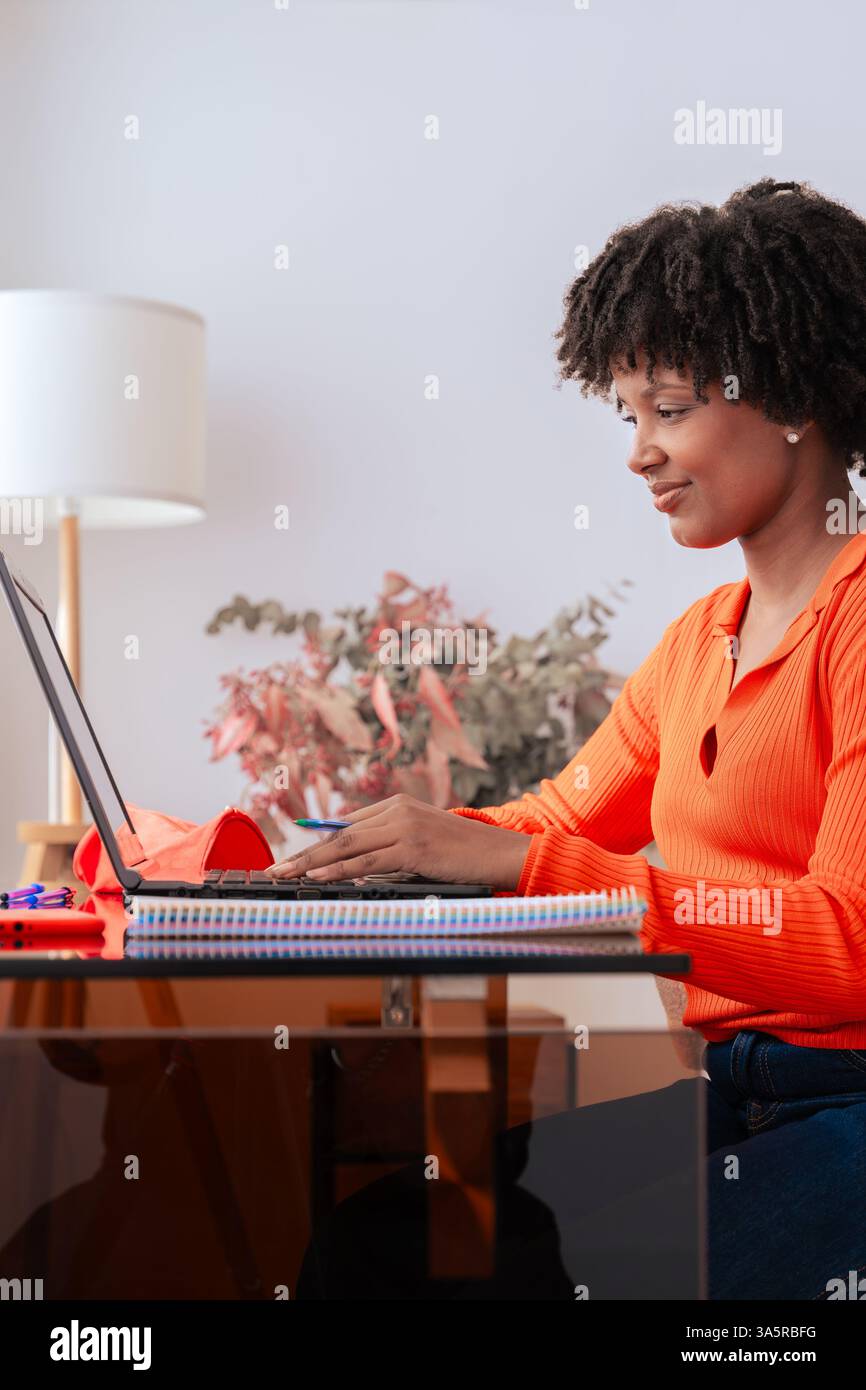 African American student studying at home, writing in notebook, using ...