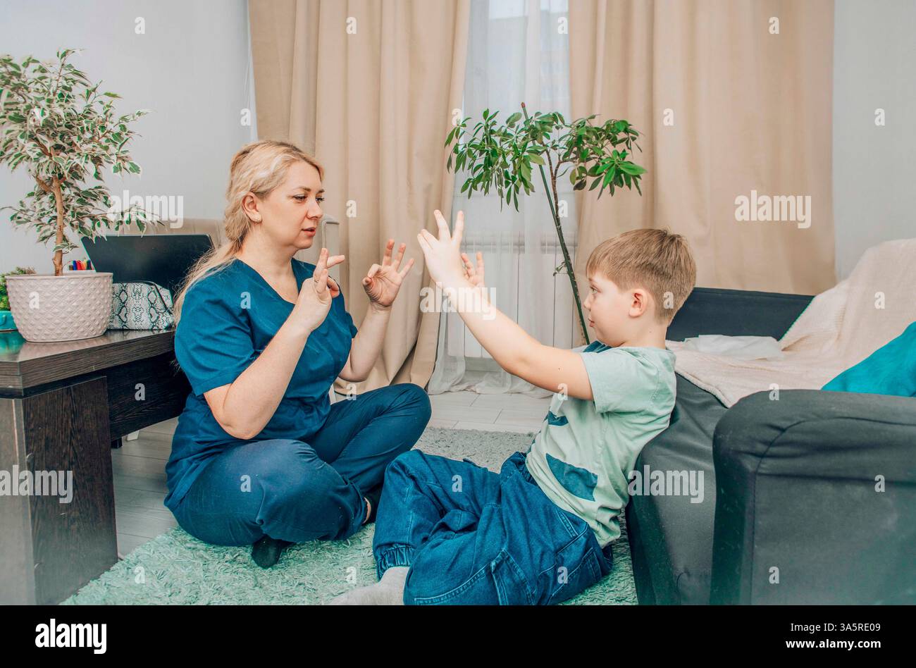 female therapist and boy practicing hand gestures in therapy session ...
