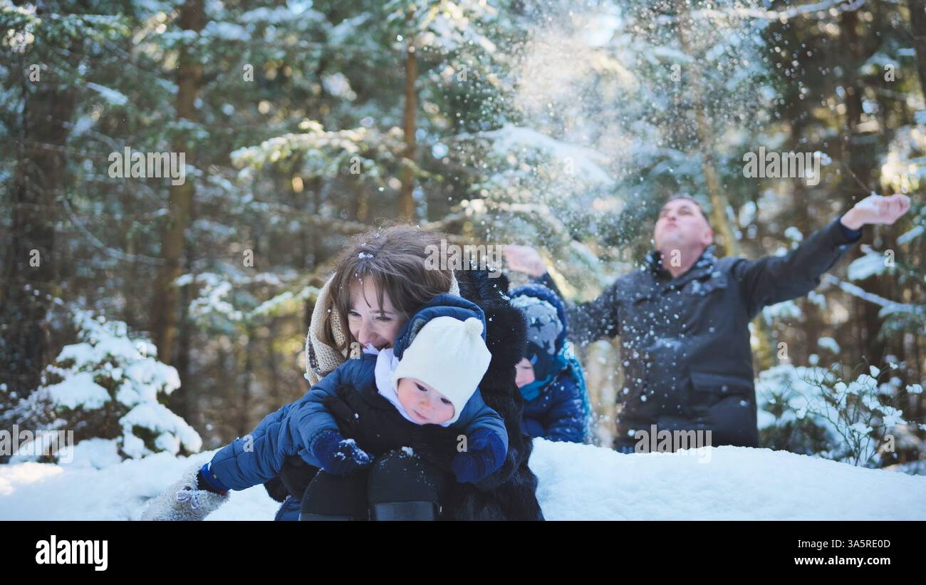 Smiling family playing, laughing while walking through snow covered ...