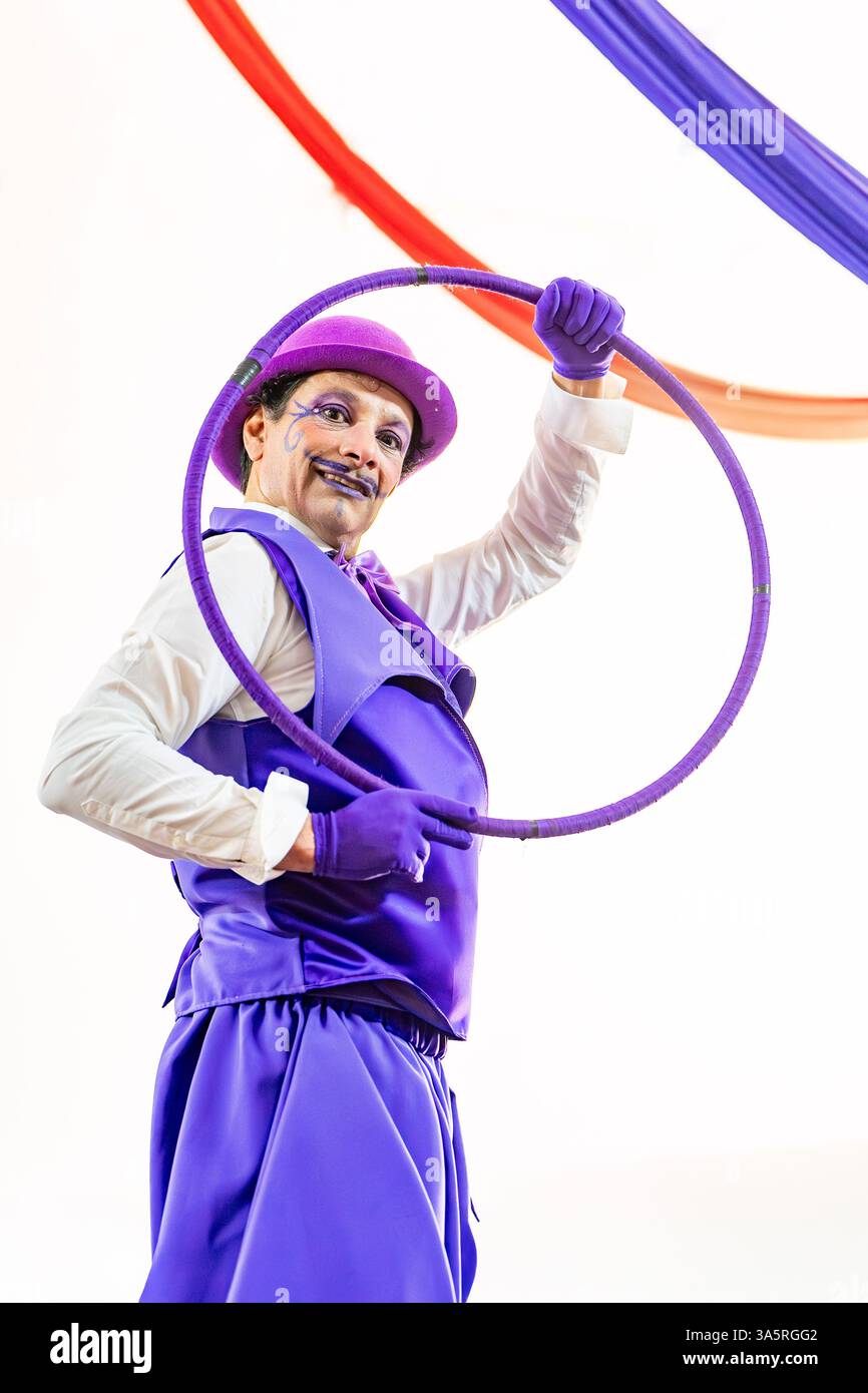 Male clown wearing purple costume and makeup holding hula hoop ...
