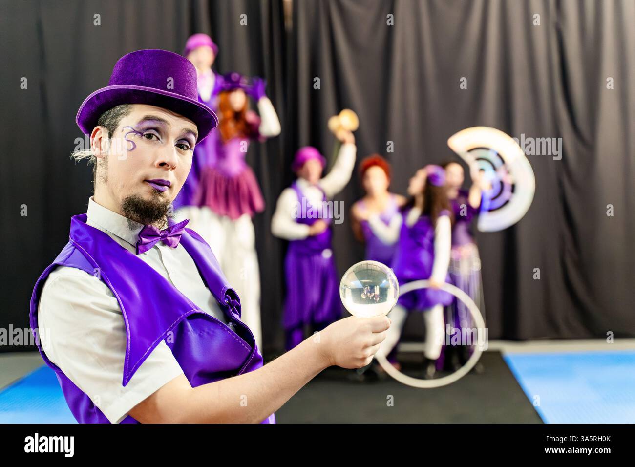 Magician wearing purple costume and top hat holding crystal ball with ...