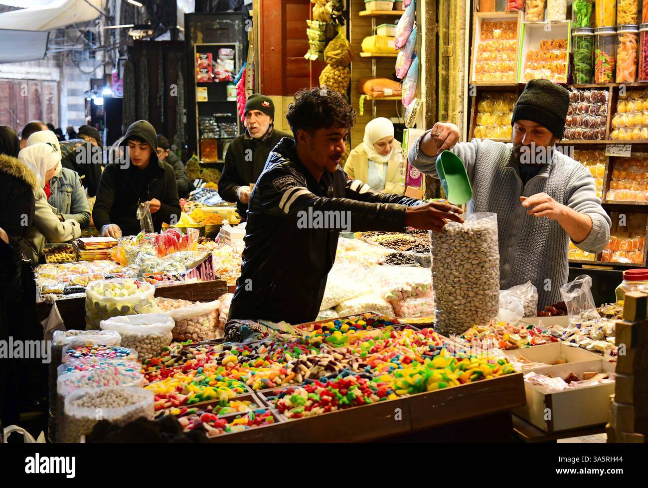 Damascus, Syria. 23rd Mar, 2025. Shoppers purchase colorful sweets and ...
