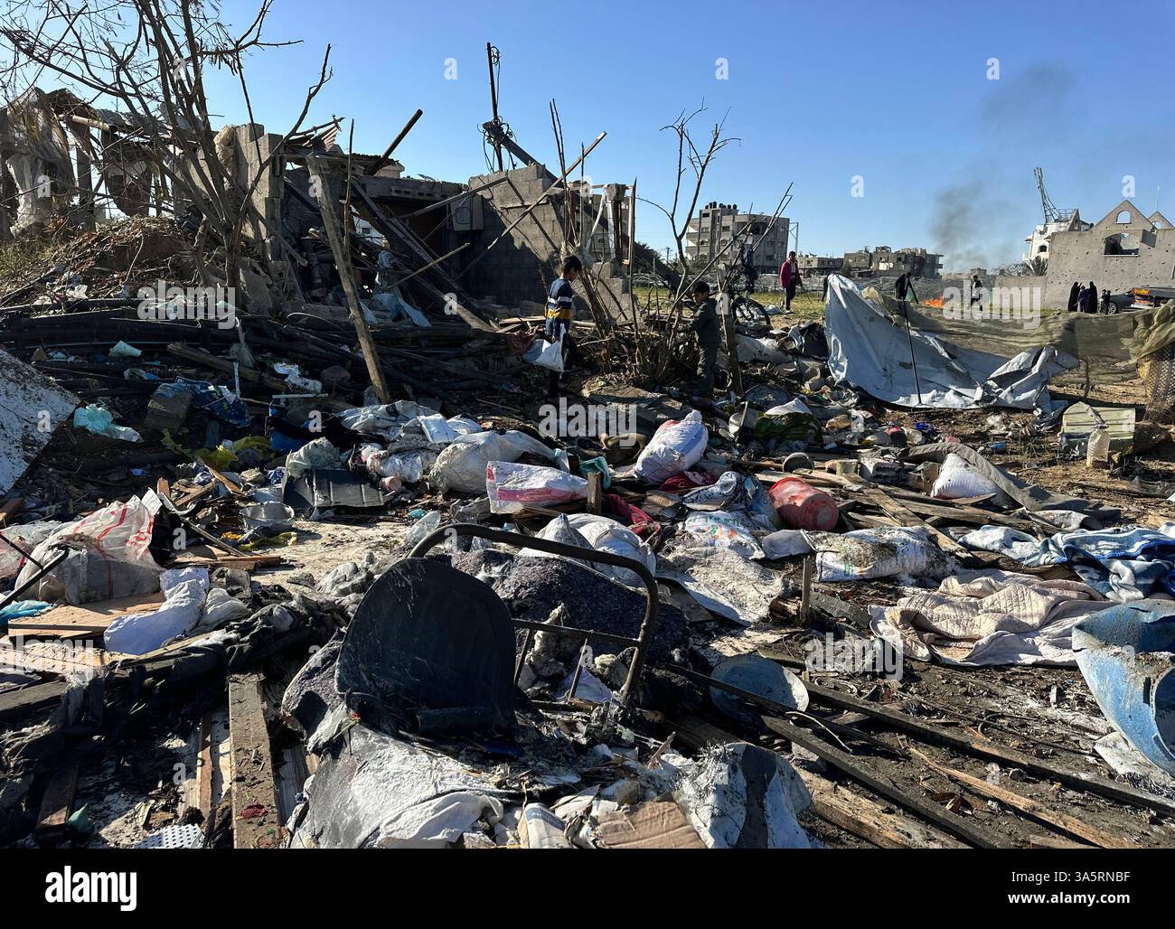 Palestinians inspect the destruction after Israeli airstrike on tents ...