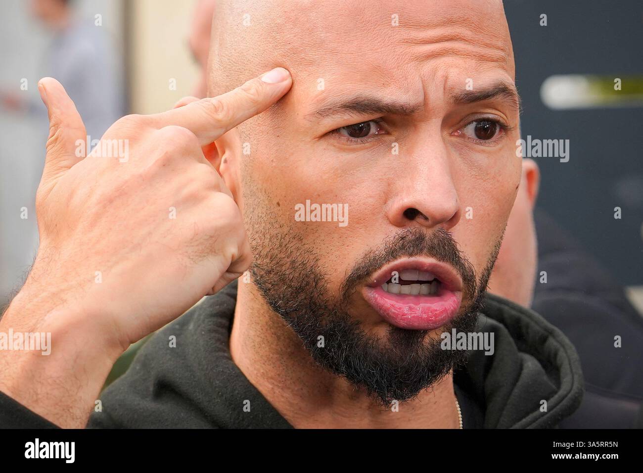 Andrew Tate gestures while speaking to media after checking in at a ...