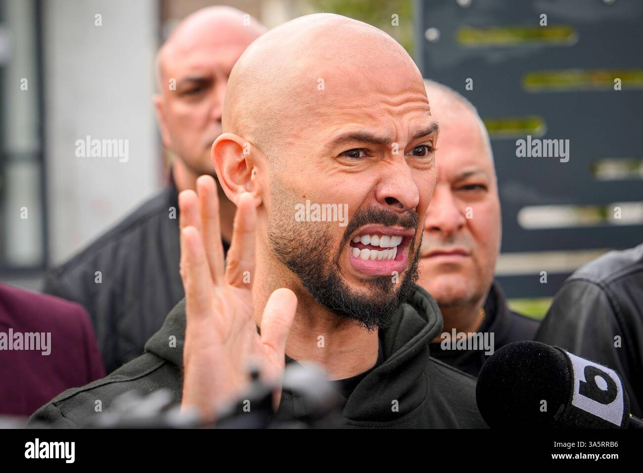 Andrew Tate gestures while speaking to media after checking in at a ...